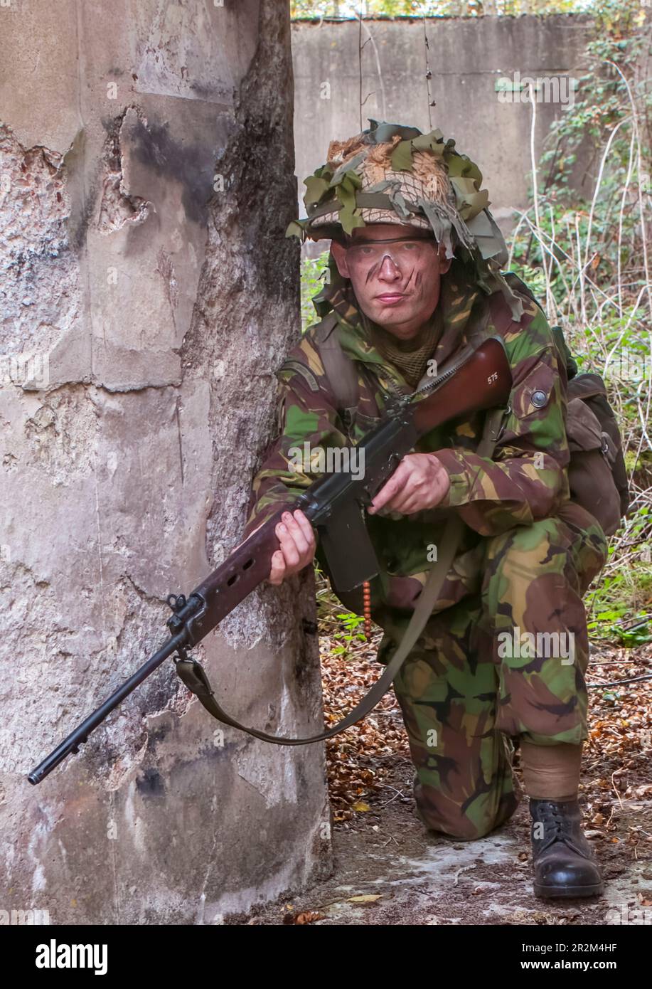 1970 British Army soldier in camouflage suit and steel helmet carrying ...