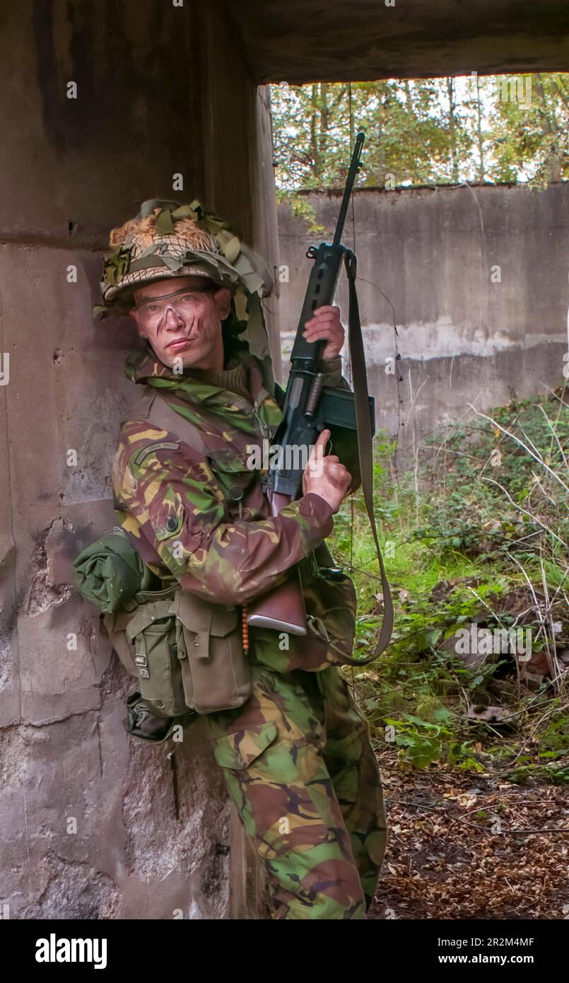 1970 British Army soldier in camouflage suit and steel helmet carrying ...