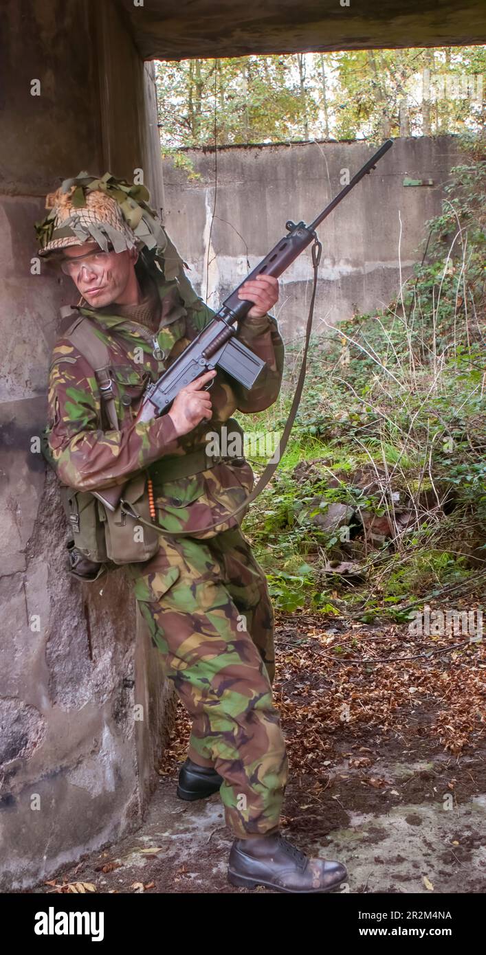 1970 British Army soldier in camouflage suit and steel helmet carrying ...