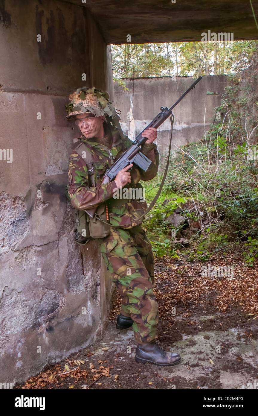 1970 British Army soldier in camouflage suit and steel helmet carrying ...