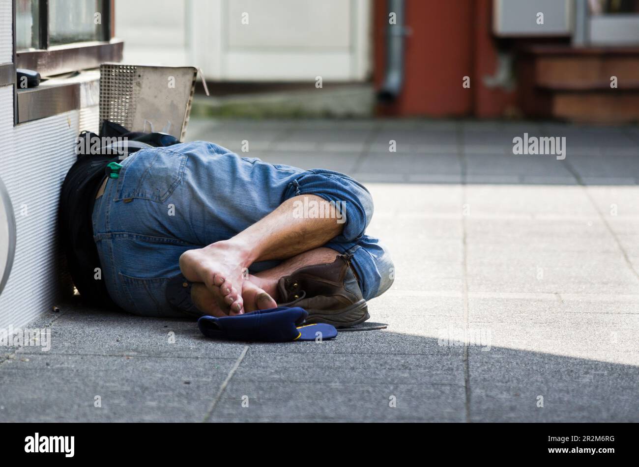 Poor tired depressed hungry homeless man or refugee sleeping on the ...