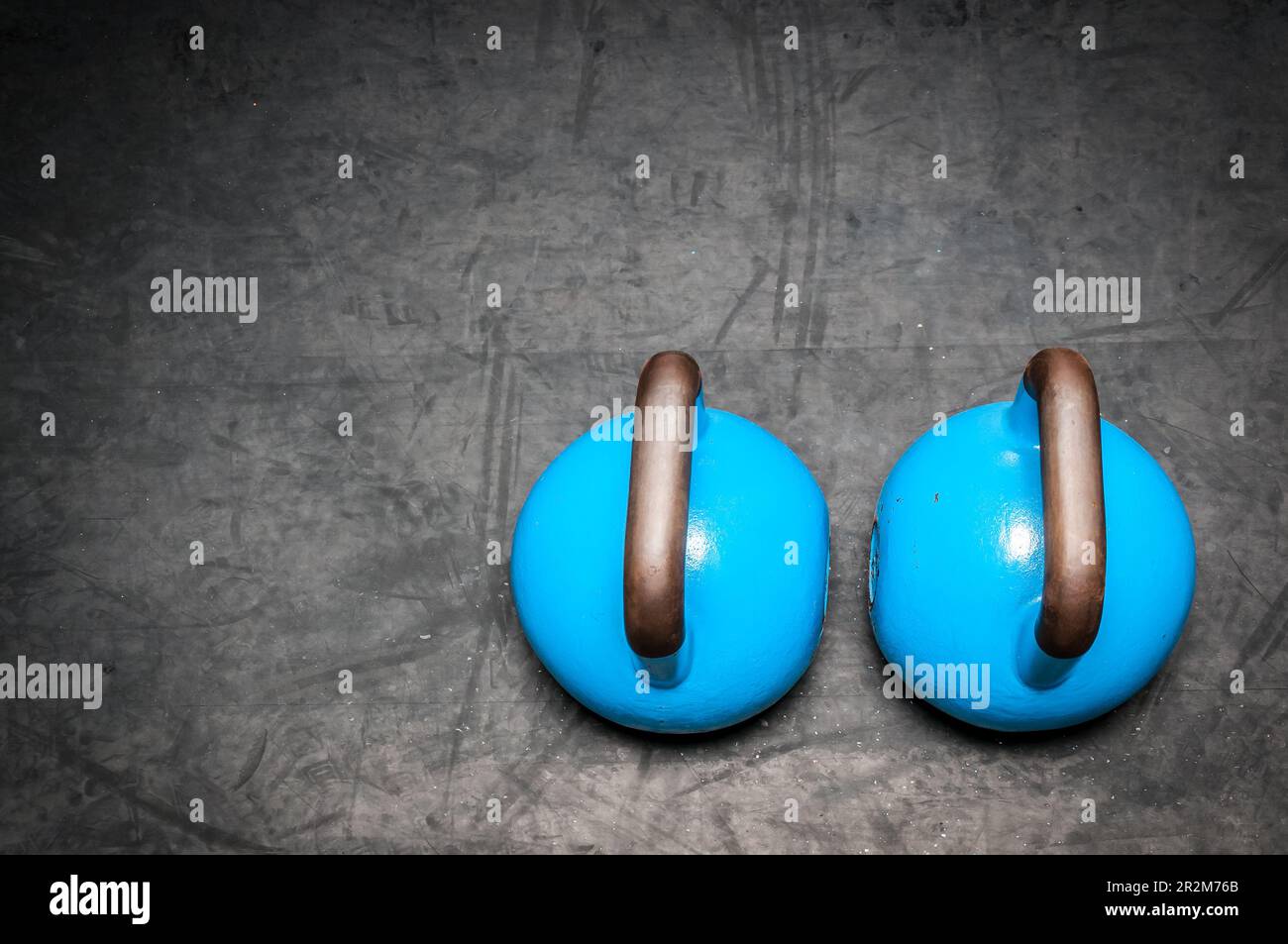 Pair of two old heavy iron kettlebells on the gym floor ready for ...
