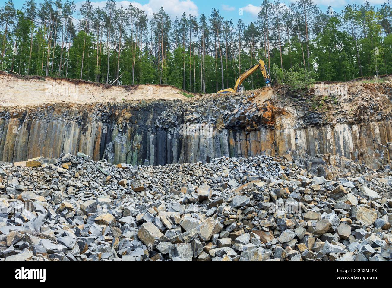 Basalt mining. Excavators in a basalt quarry near the forest. Large ...