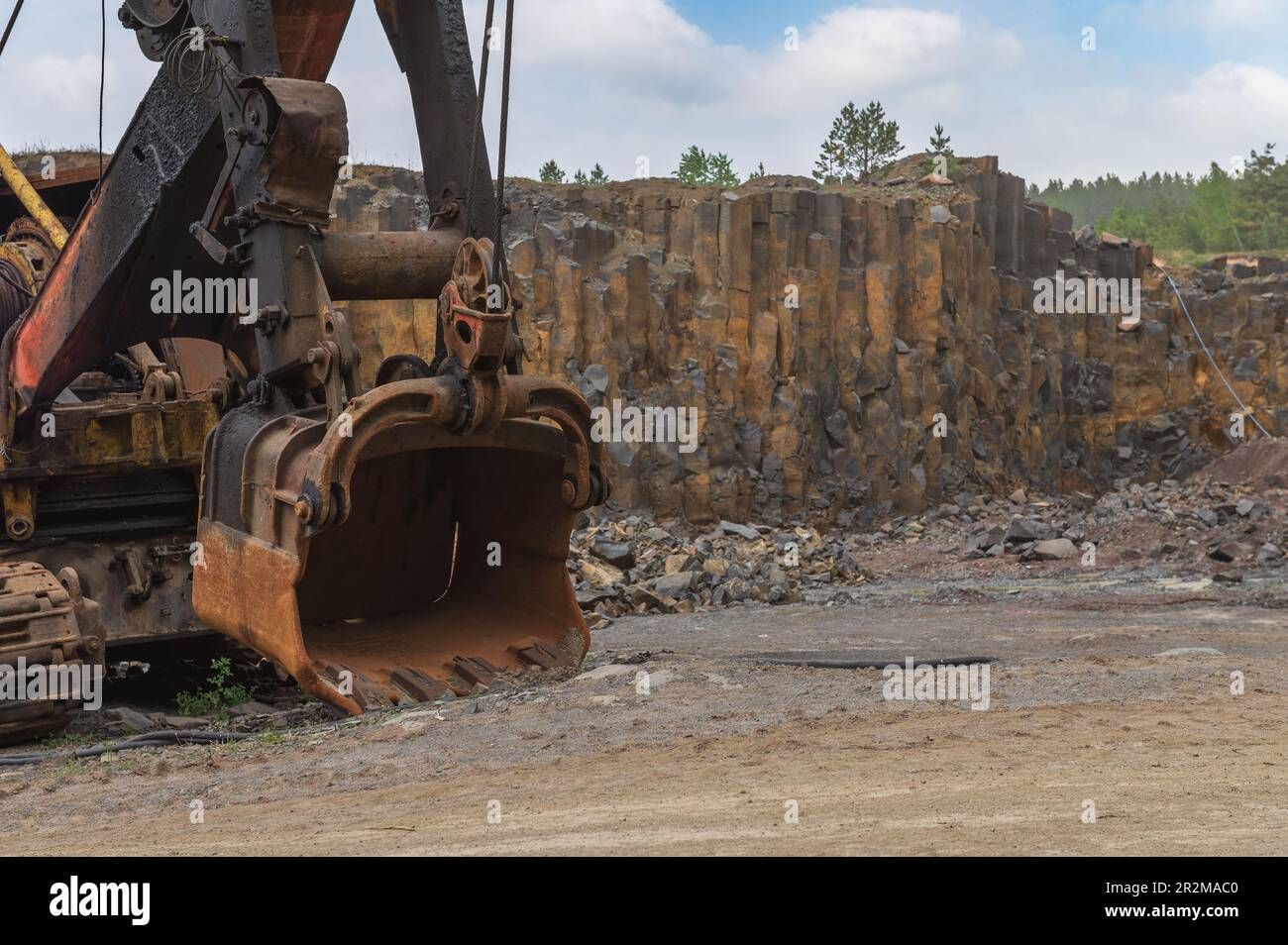 Basalt mining. Excavators in a basalt quarry near the forest. Large ...