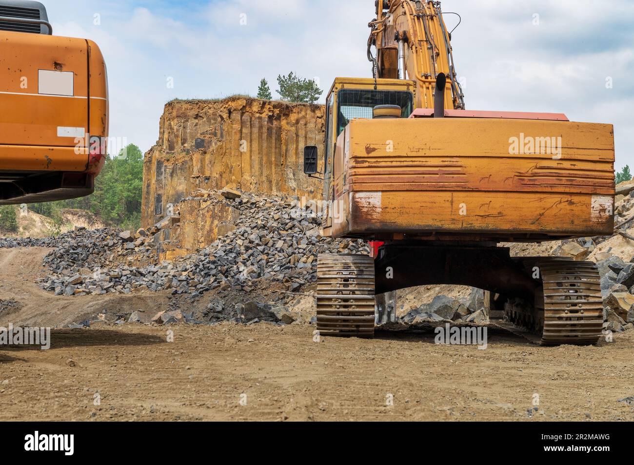 Basalt mining. Yellow excavators in a basalt quarry near the forest ...