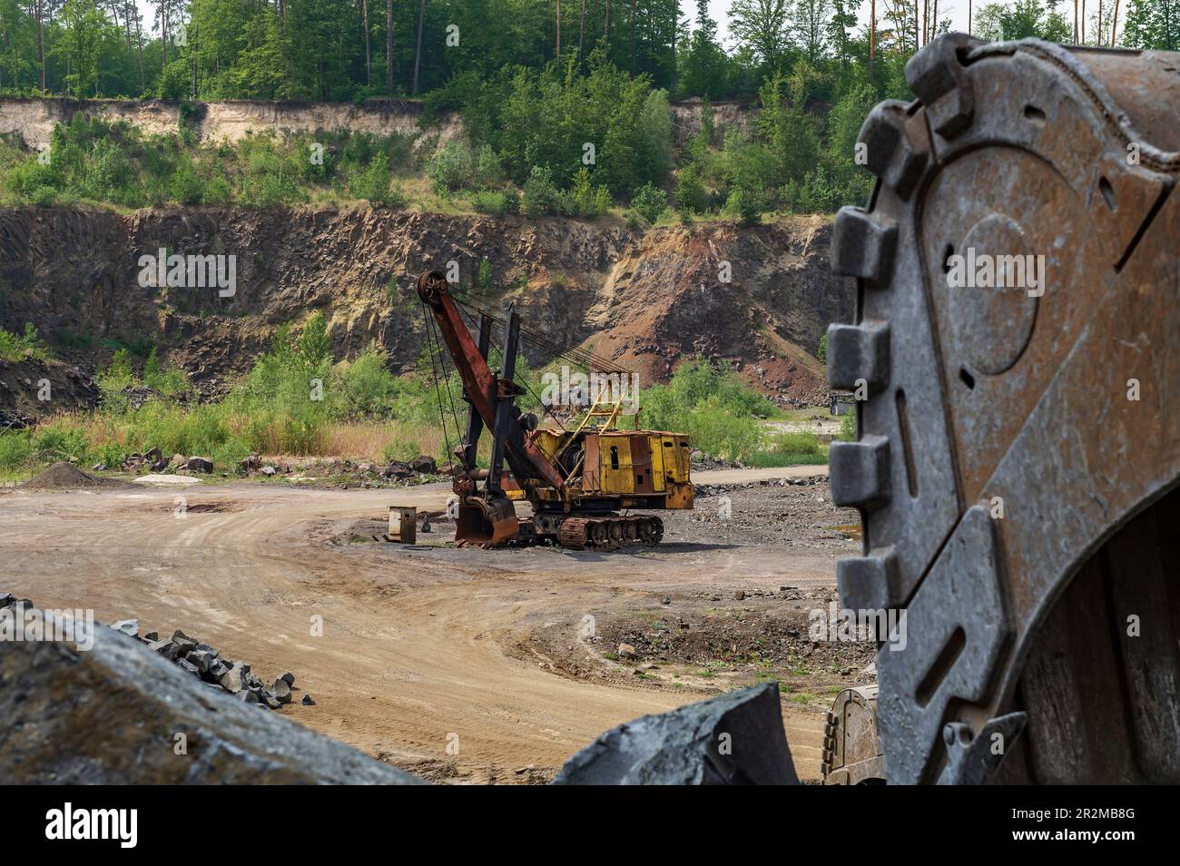 Basalt mining. Yellow excavators in a basalt quarry near the forest ...