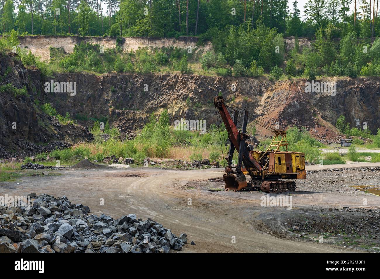 Basalt mining. Yellow excavators in a basalt quarry near the forest ...