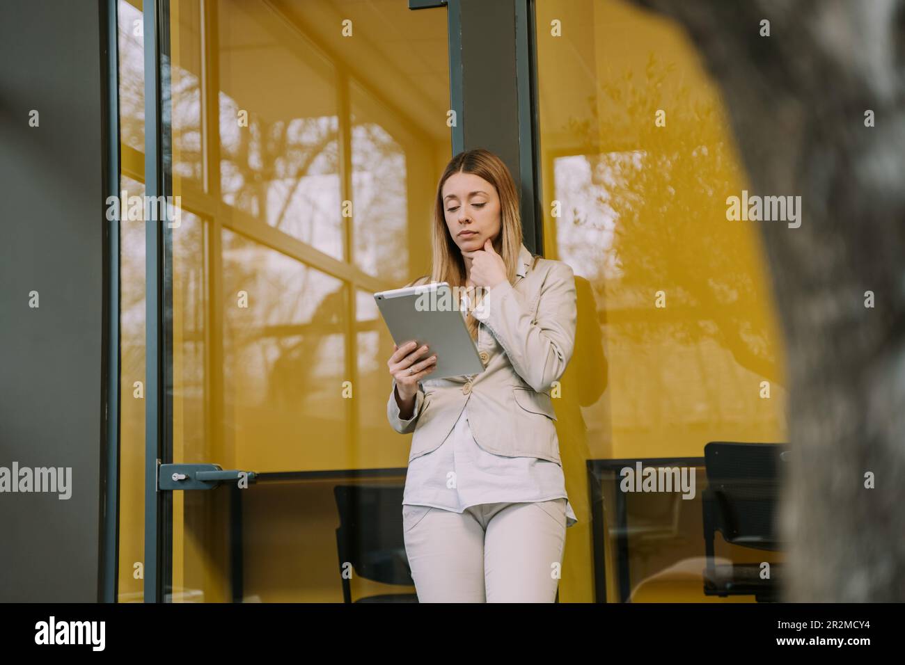 Beautiful blonde girl is checking something on her tablet and thinking ...