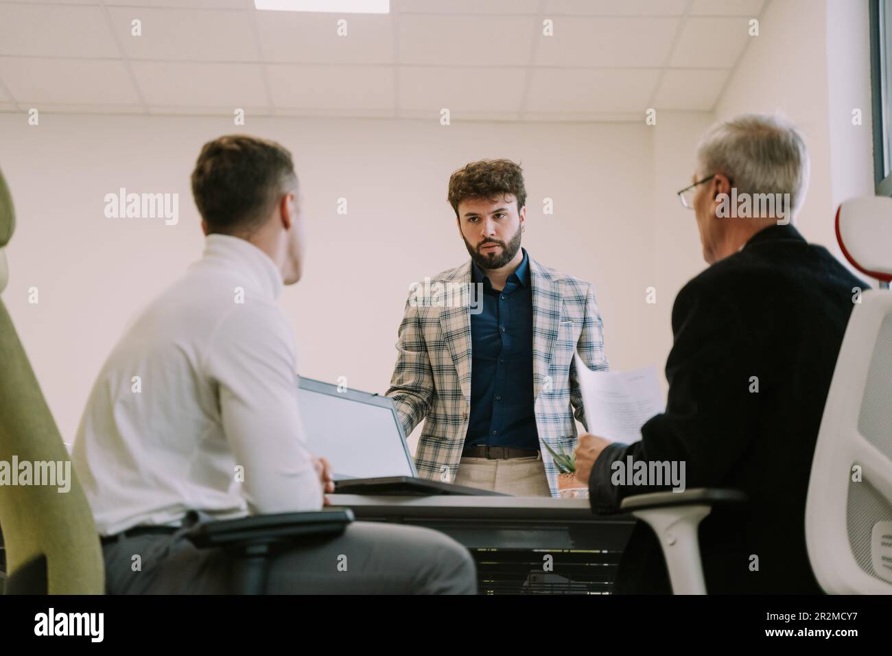 Disappointed and angry boss overlooking and correcting his employees at ...