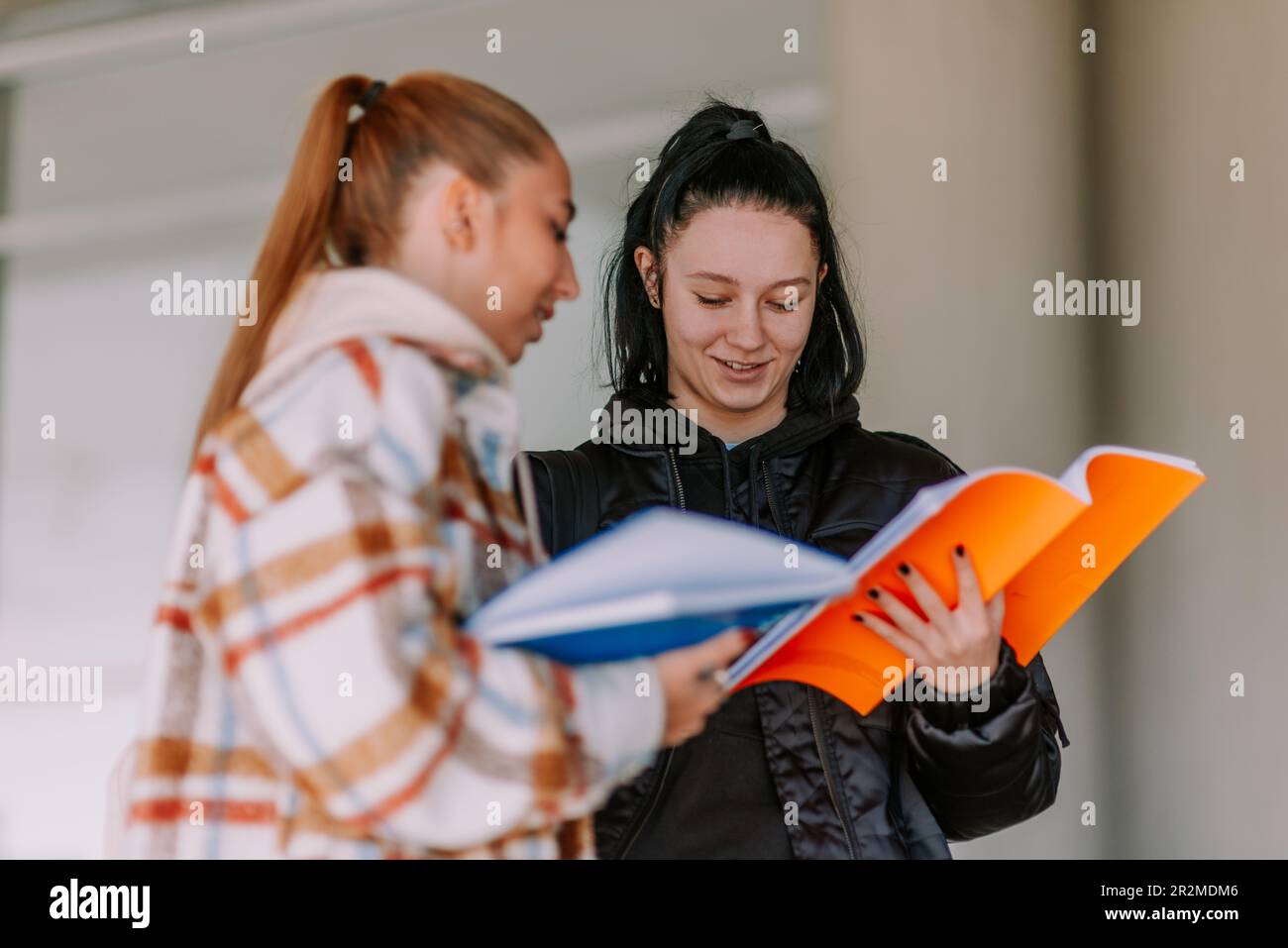 Two beautiful high school best friends are having a fun conversation ...