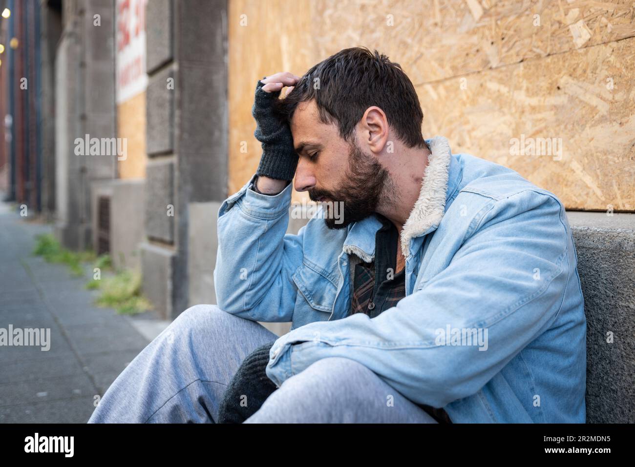 Young sad sick poor homeless man sitting on the street need help ...