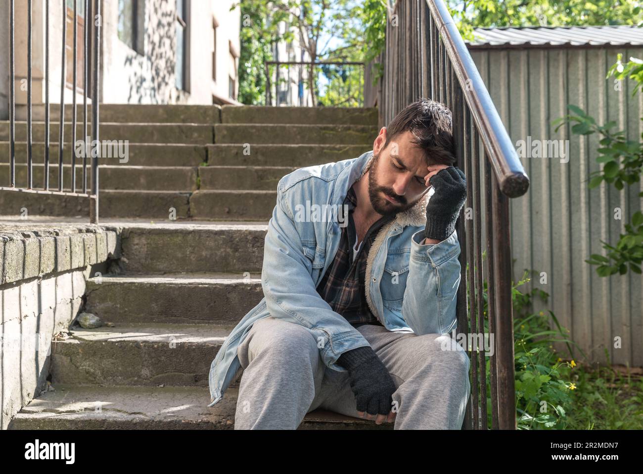 Young sad sick poor homeless man sitting on the street need help ...