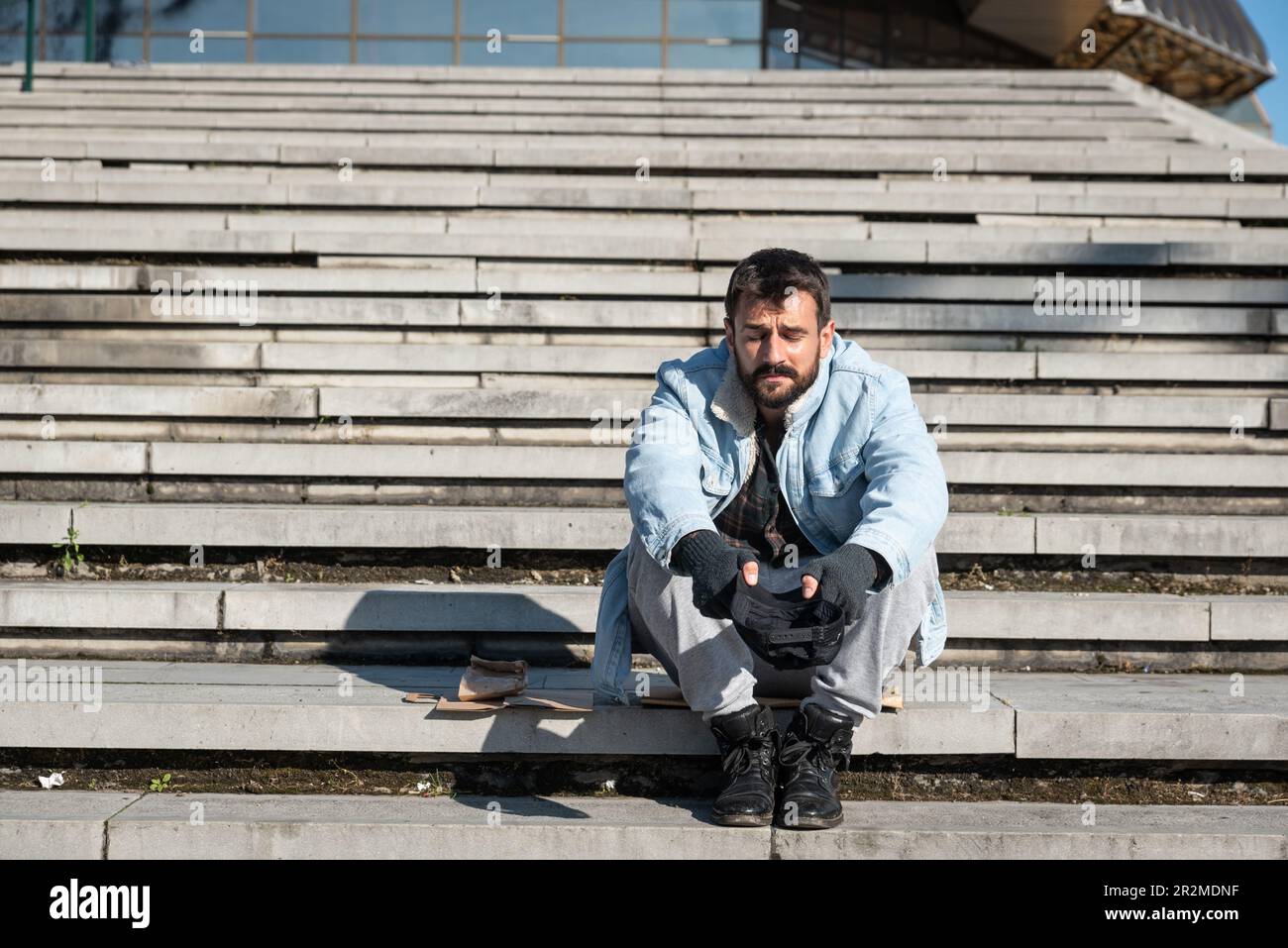 Young sad sick poor homeless man sitting on the street need help ...