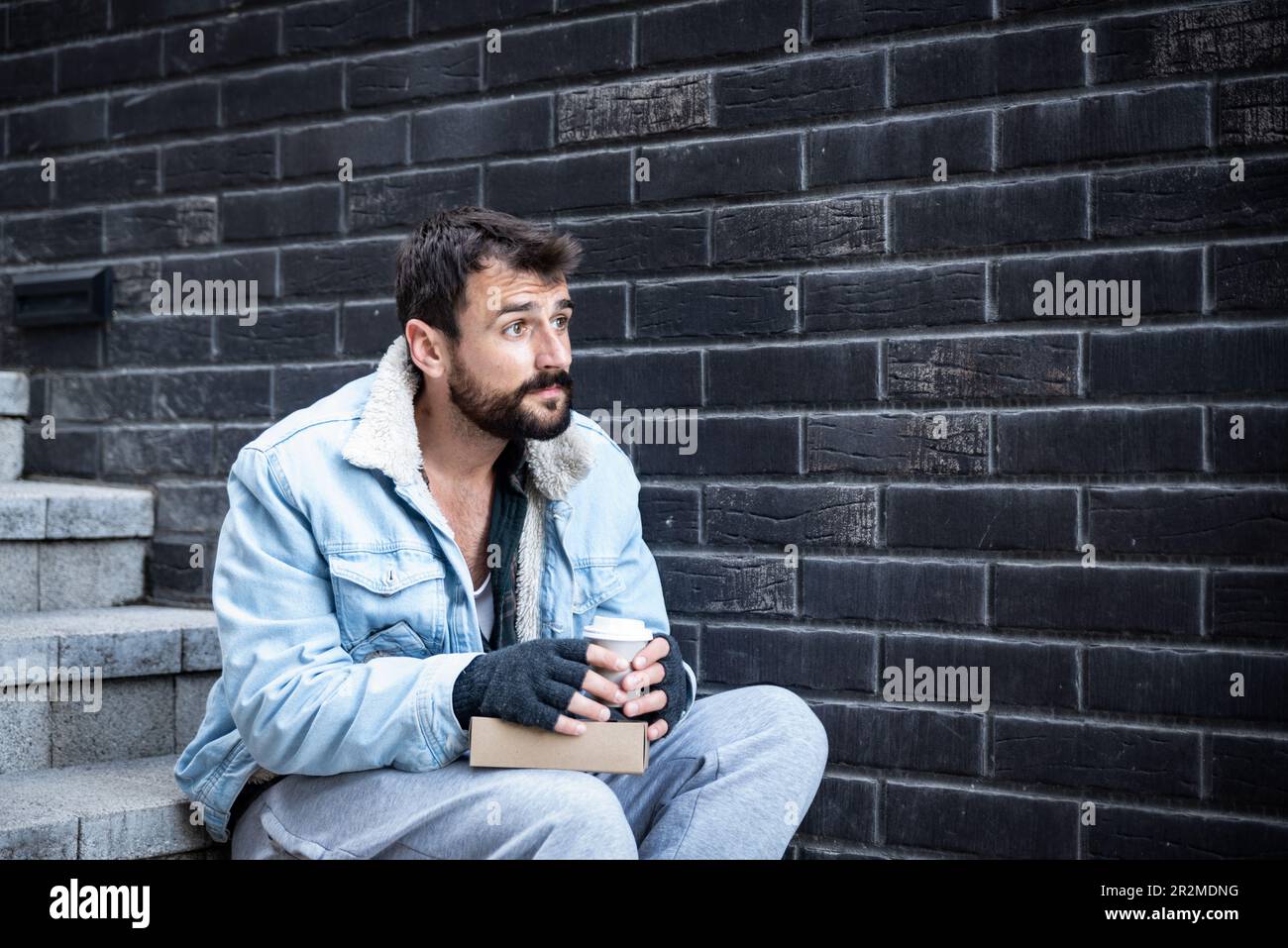 Young sad sick poor homeless man sitting on the street need help ...