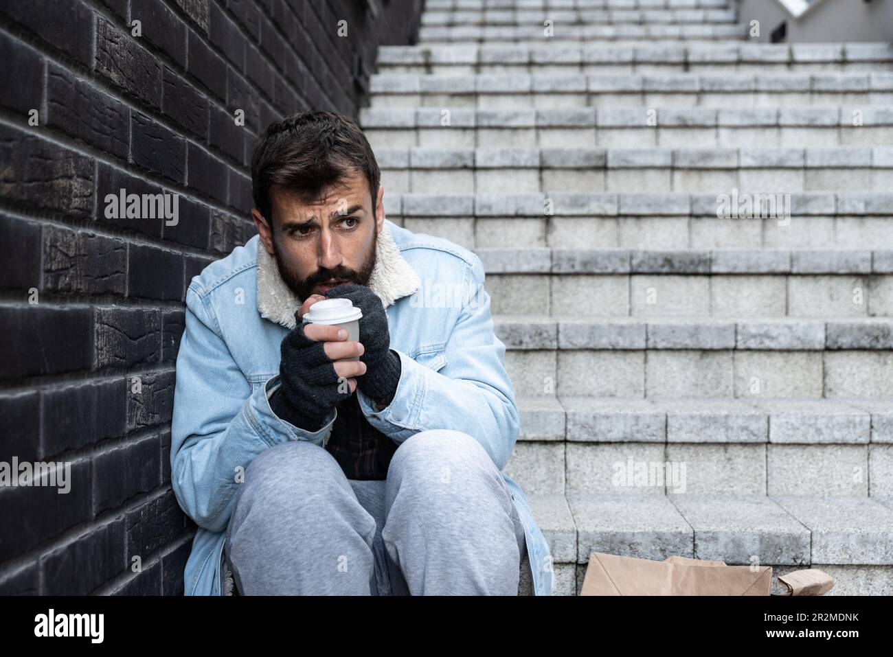 Young sad sick poor homeless man sitting on the street need help ...