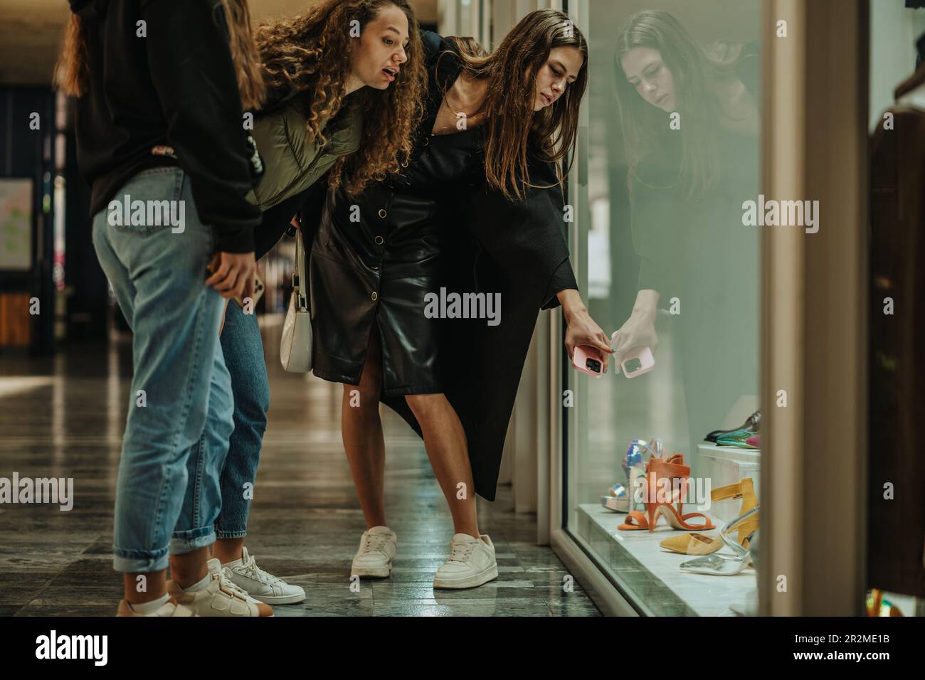 Girls looking at the shop window in the shopping mall. Brunette girl ...