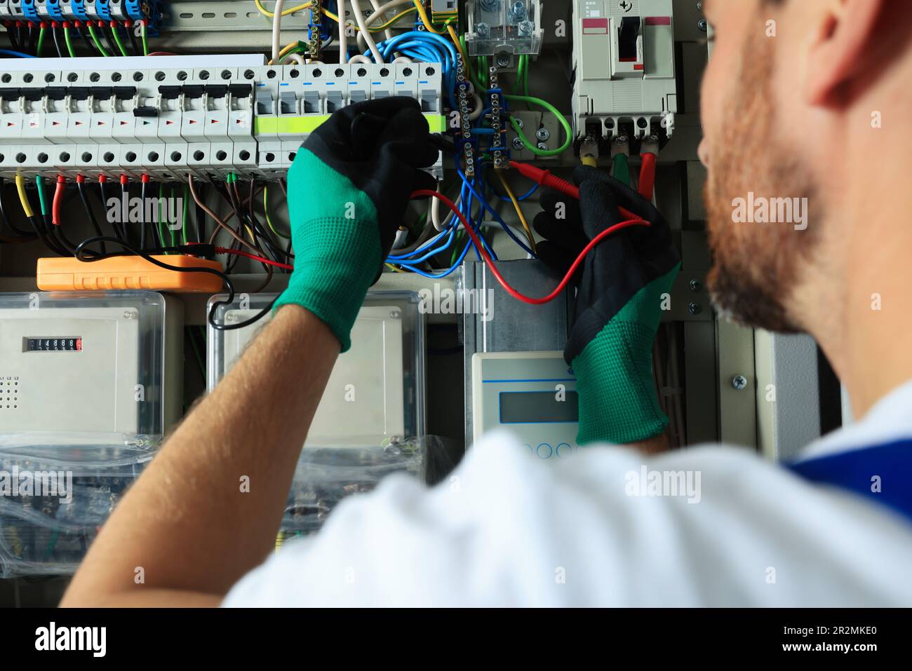 Electrician checking electric current with multimeter indoors, closeup ...