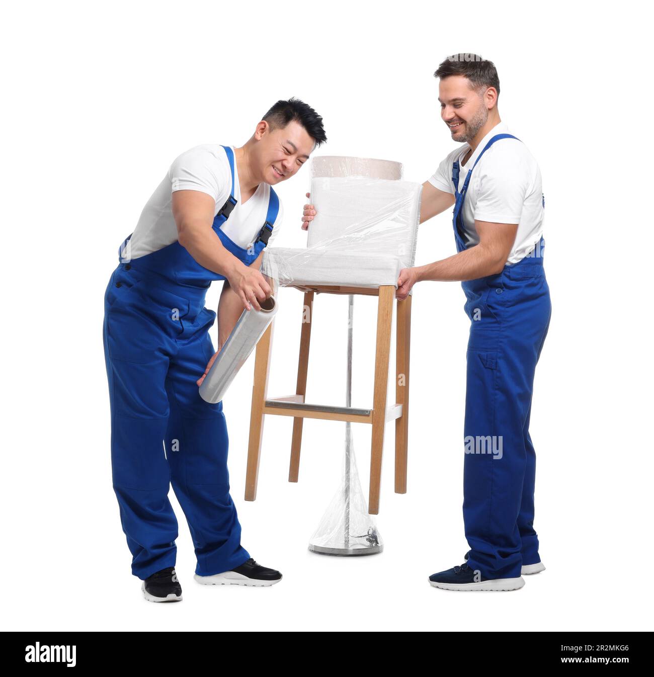 Workers wrapping chair in stretch film on white background Stock Photo ...