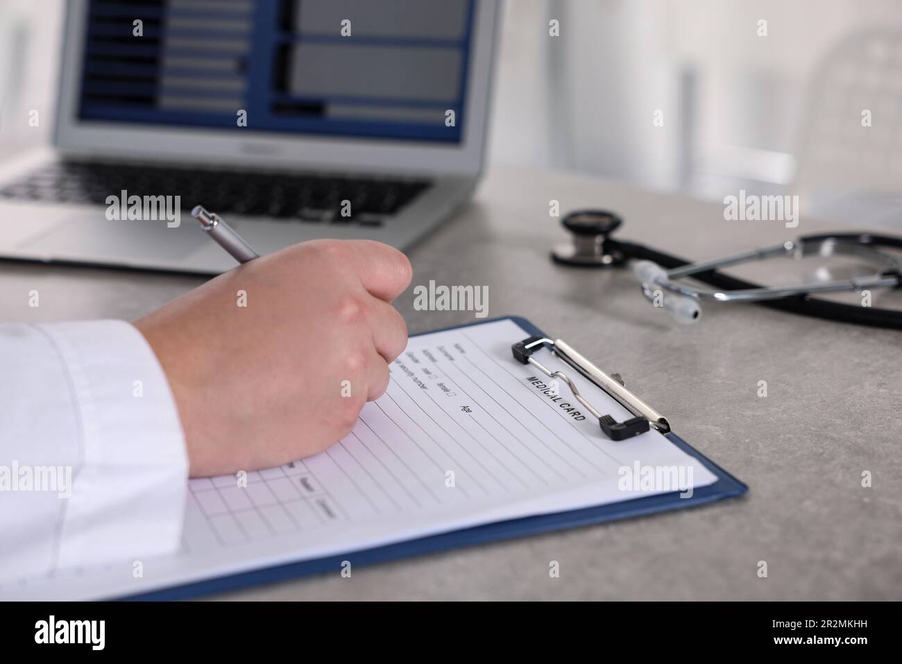 Doctor filling out patient's medical card at table in clinic, closeup ...