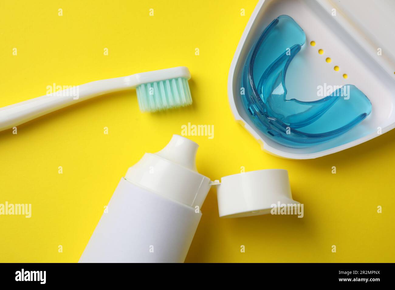 Toothpaste, brush and dental mouth guard on yellow background, flat lay ...