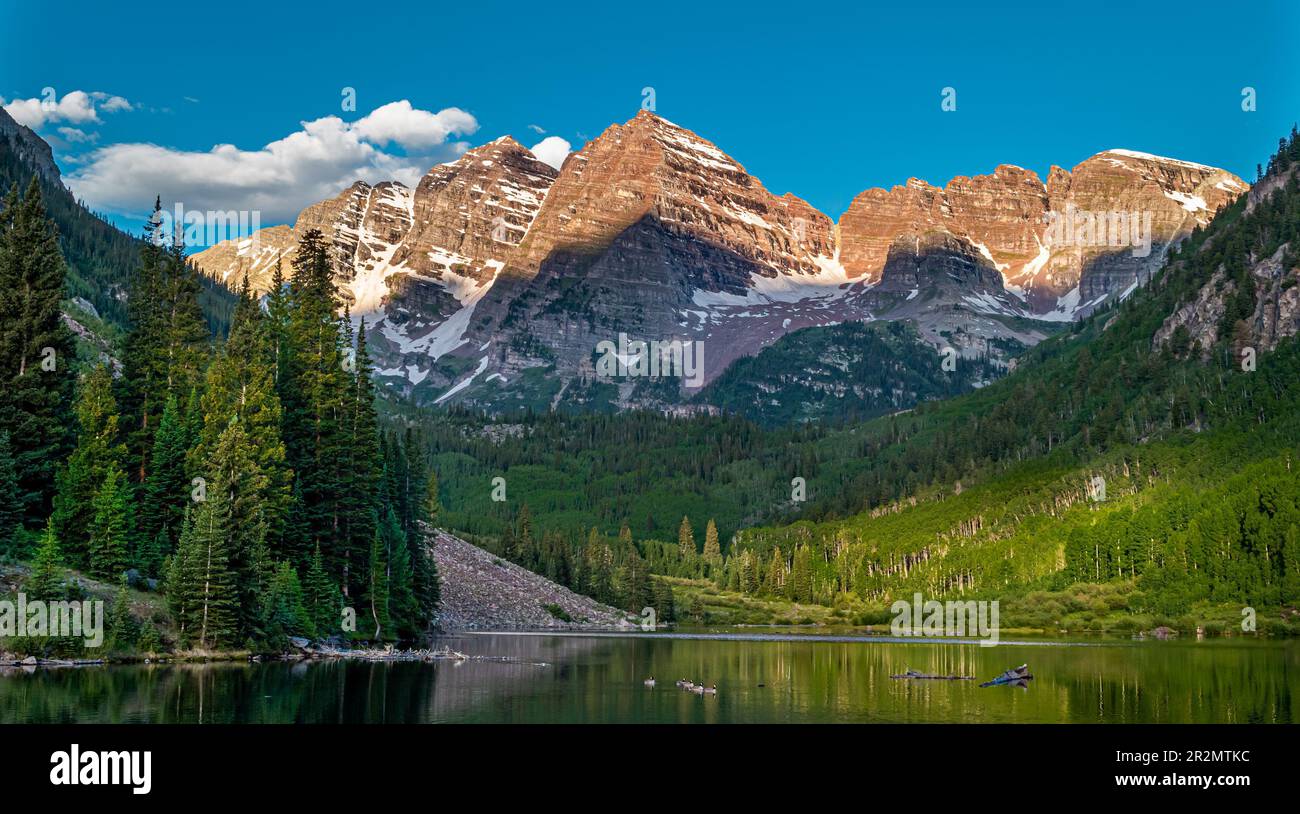 The Maroon Bells being lit by an early morning sun above the clear ...