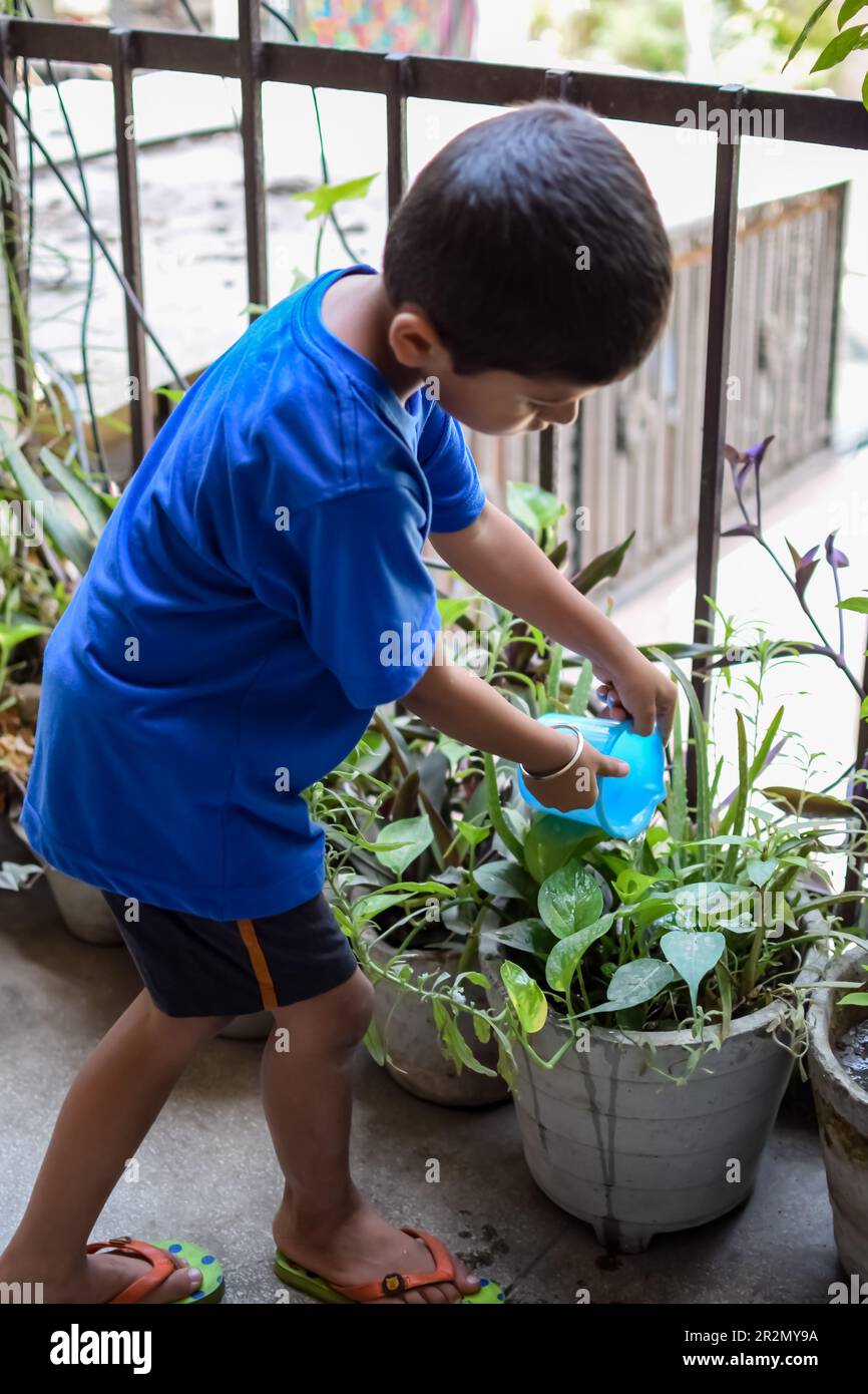 Cute 5 year’s old Asian little boy is watering the plant in the pots ...