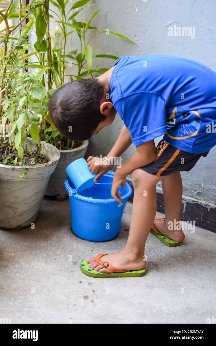 Cute 5 year’s old Asian little boy is watering the plant in the pots ...