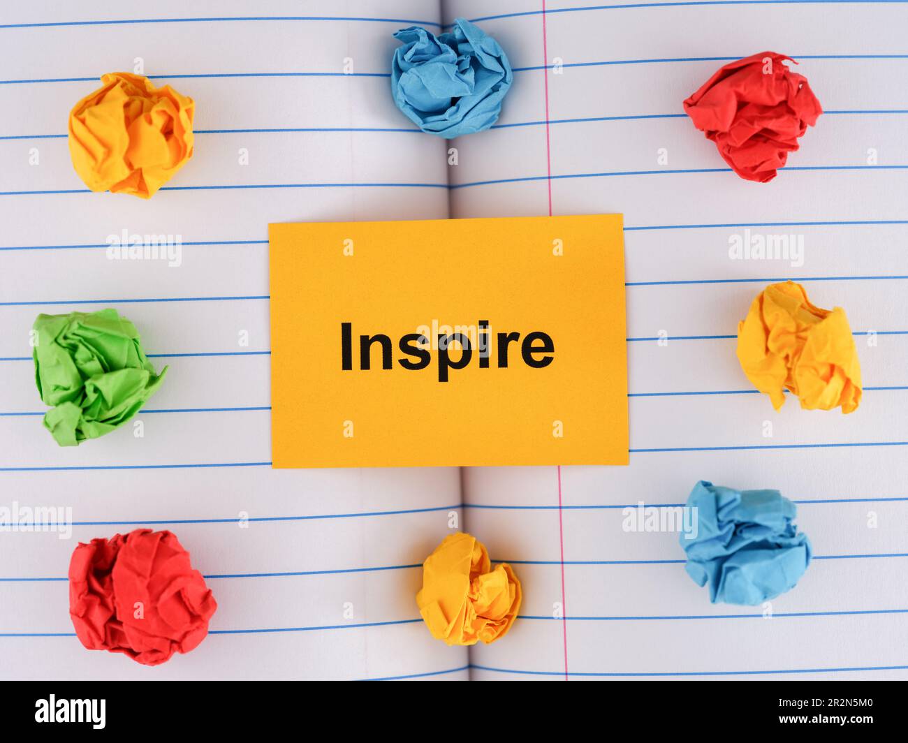A yellow paper note with the word Inspire on notebook sheet with some ...