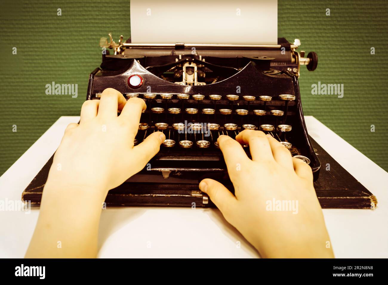 Hands are typing on vintage typewriter filled with white blank sheet of ...