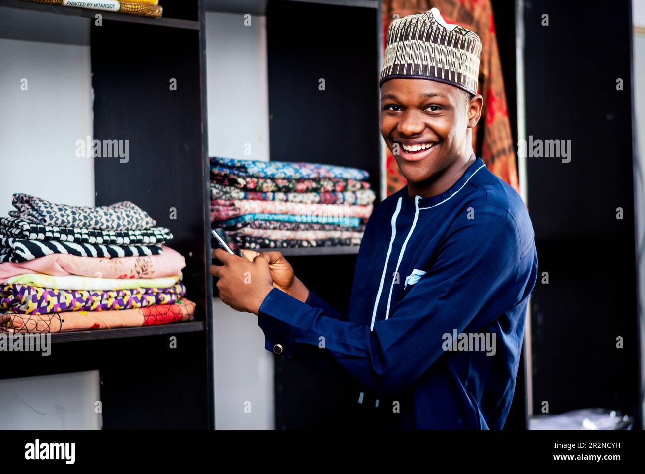 Photo of a stylish African man posing in front of a clothing rack Stock ...