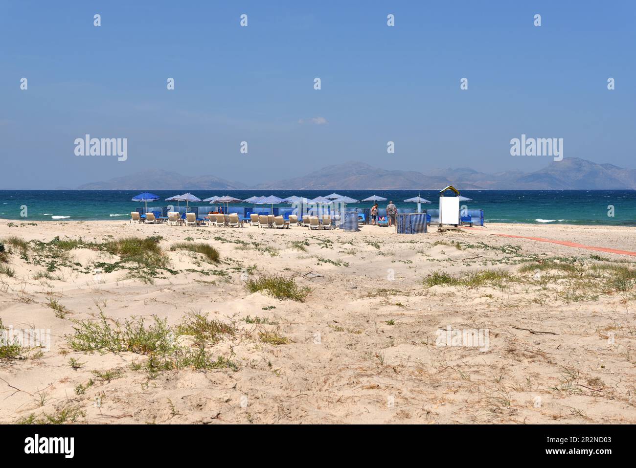 Kos, Greece - May 7, 2023: Sun loungers on sandy beach of Marmari. The ...