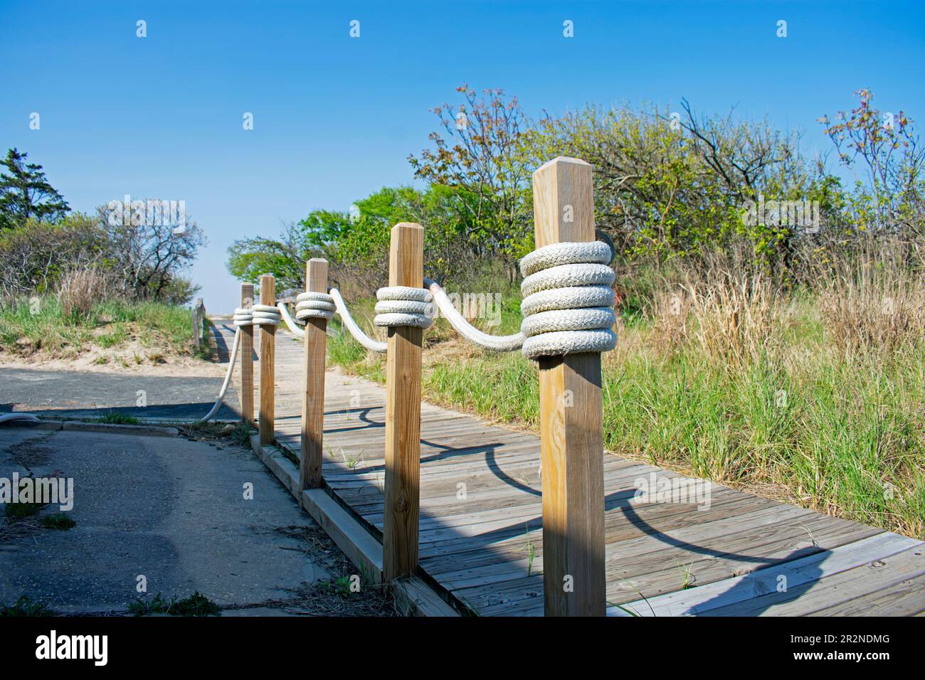 Wooden boardwalk path with corded handrail between two beach parking ...