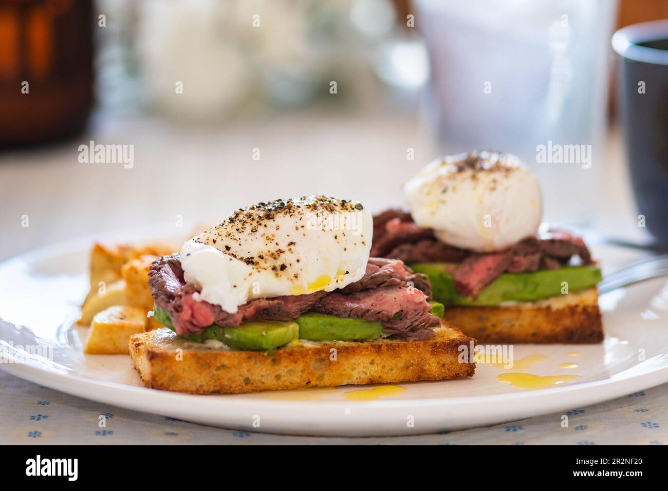 Steak benedict breakfast. Poached eggs, grilled steak and avocado on ...