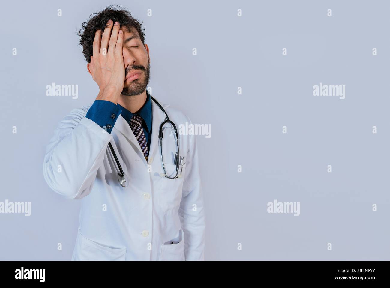 Exhausted doctor with hand on his forehead. Overworked doctor with hand ...