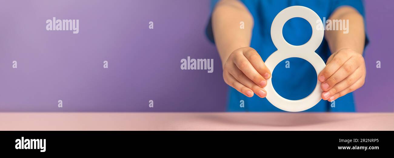 Number 8 in hand. A hand holds a white number eight on a purple ...