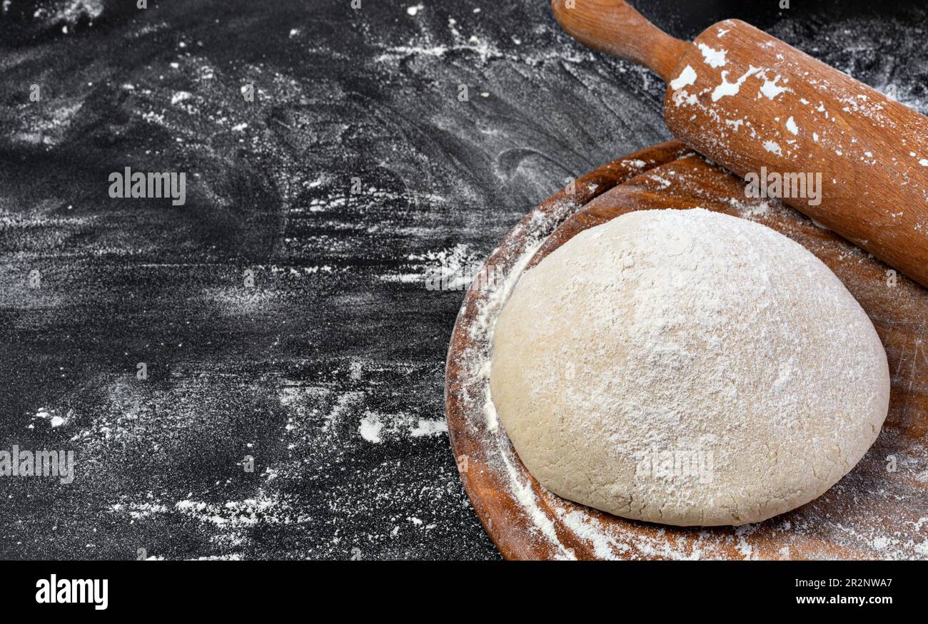 Preparation of the dough. The rolling pin with flour on a dark ...