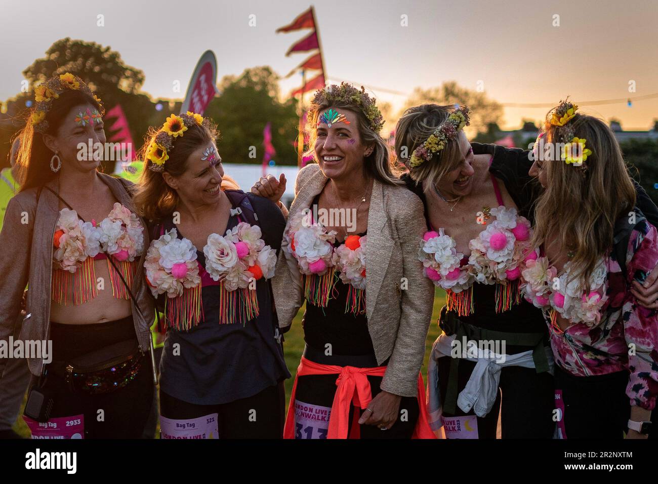 A group of walkers gather during sunset at the start of Moonwalk London ...