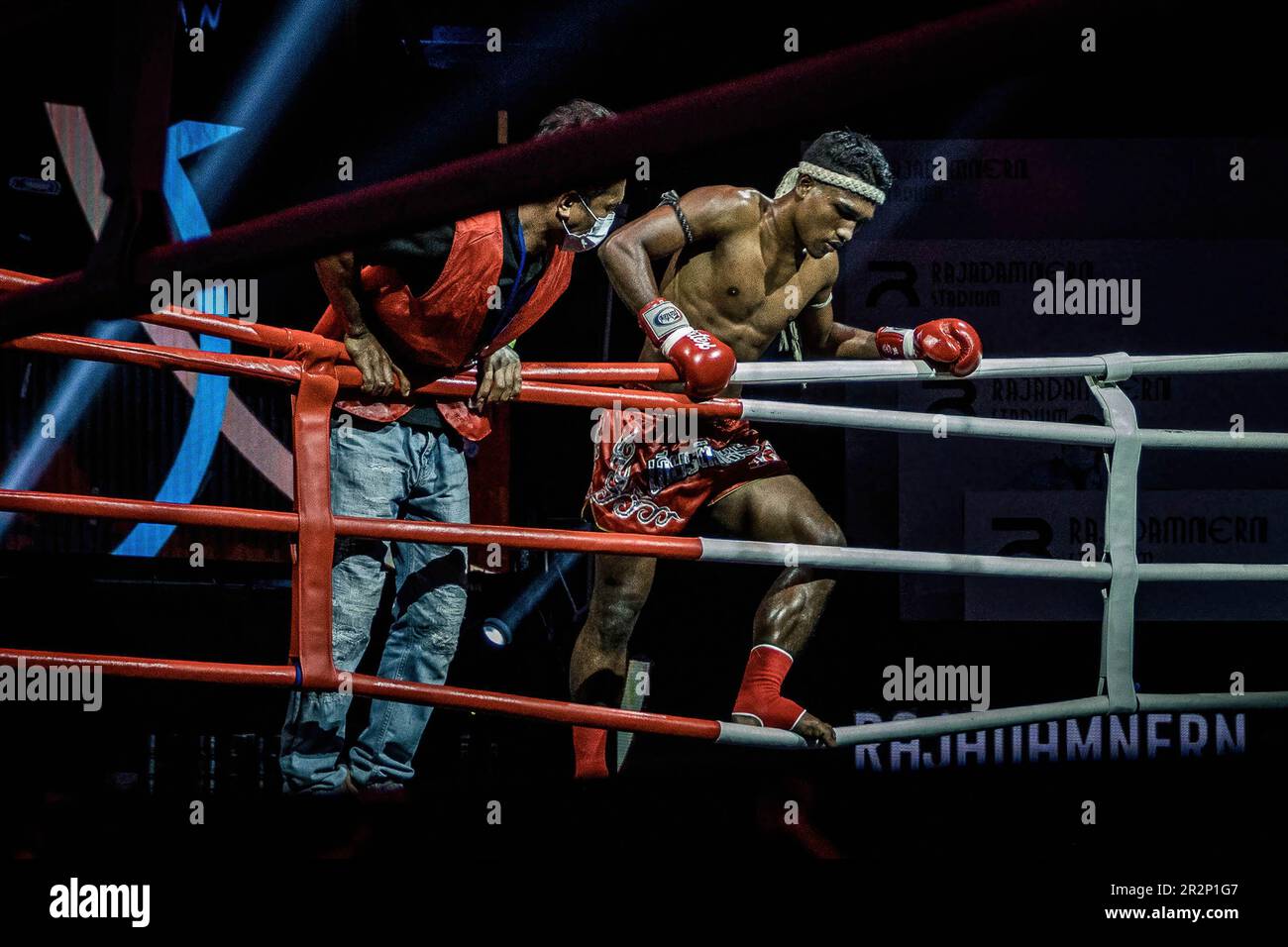 A Muay Thai boxer receives advice from his coach between rounds, at ...