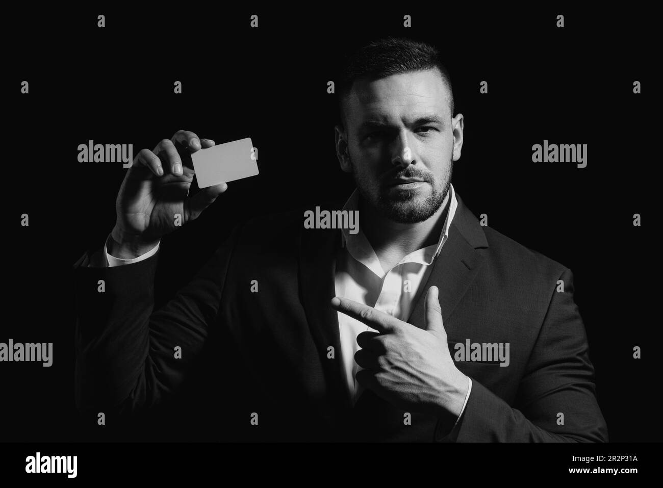 Portrait of a young man dressed in suit pointing finger at a credit ...