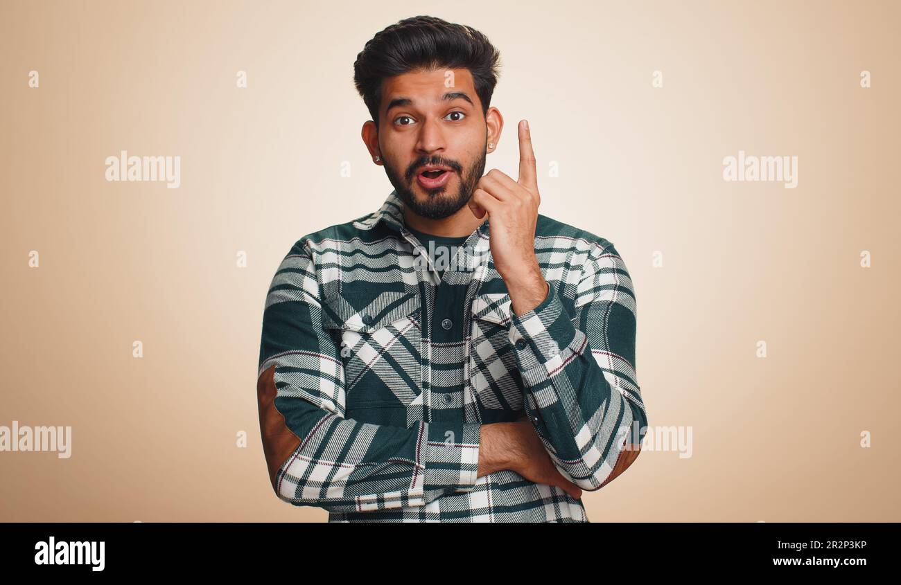 Eureka. Inspired young indian man pointing finger up with open mouth ...