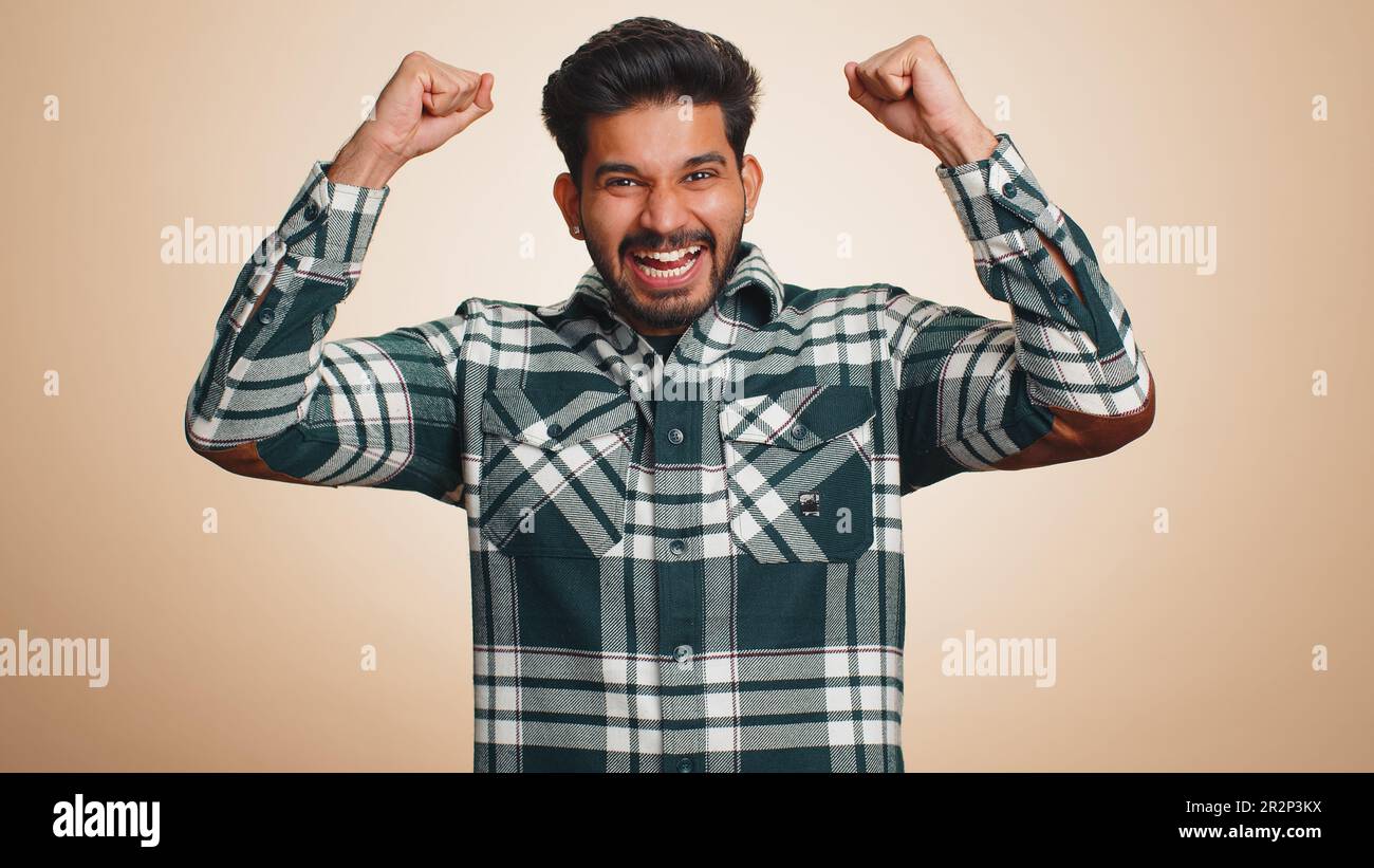 Happy joyful indian man shouting, raising fists in gesture I did it ...