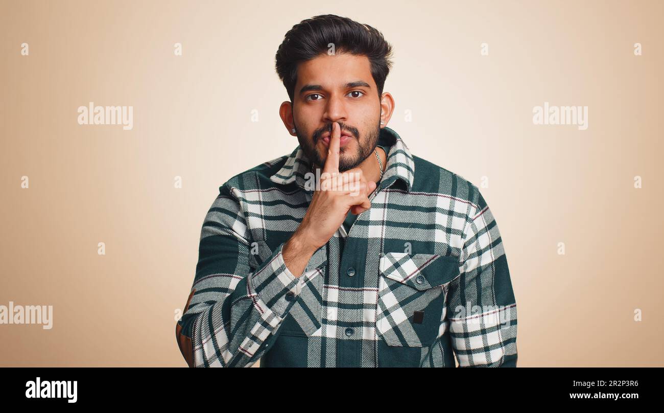 Shh be quiet please. Young indian man presses index finger to lips ...