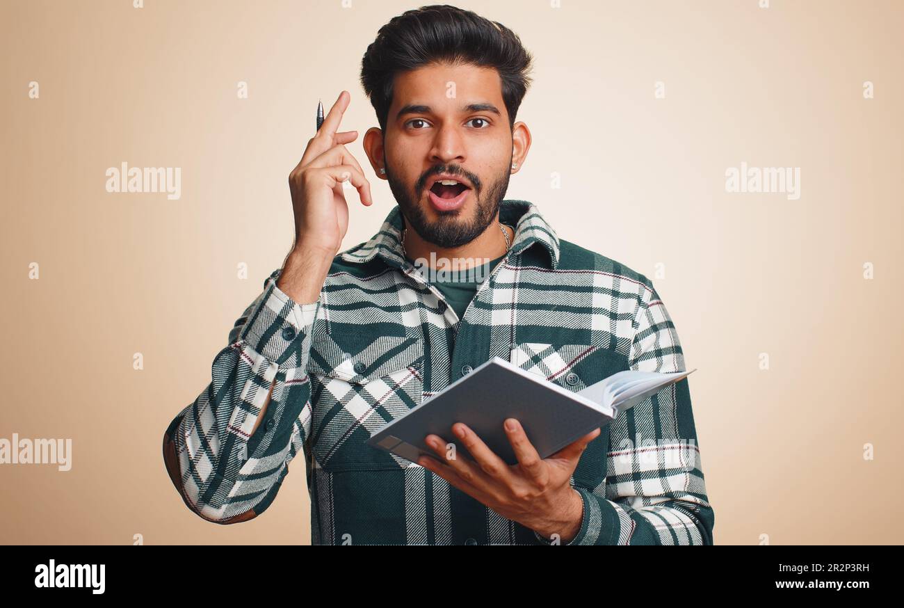 Thoughtful journalist indian man making notes, writing down thoughts ...