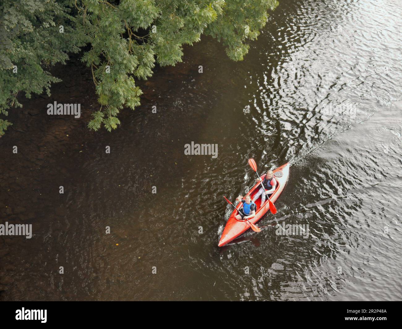 Two canoeists wave as they approach Hay Bridge on the River Wye, Powys ...