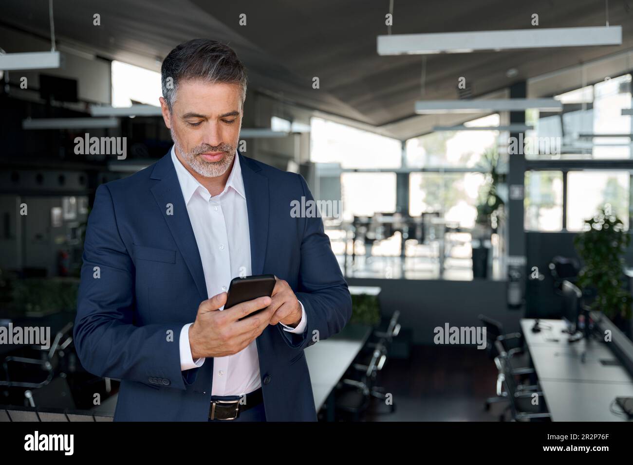 Busy middle aged business man ceo standing in office using mobile cell ...