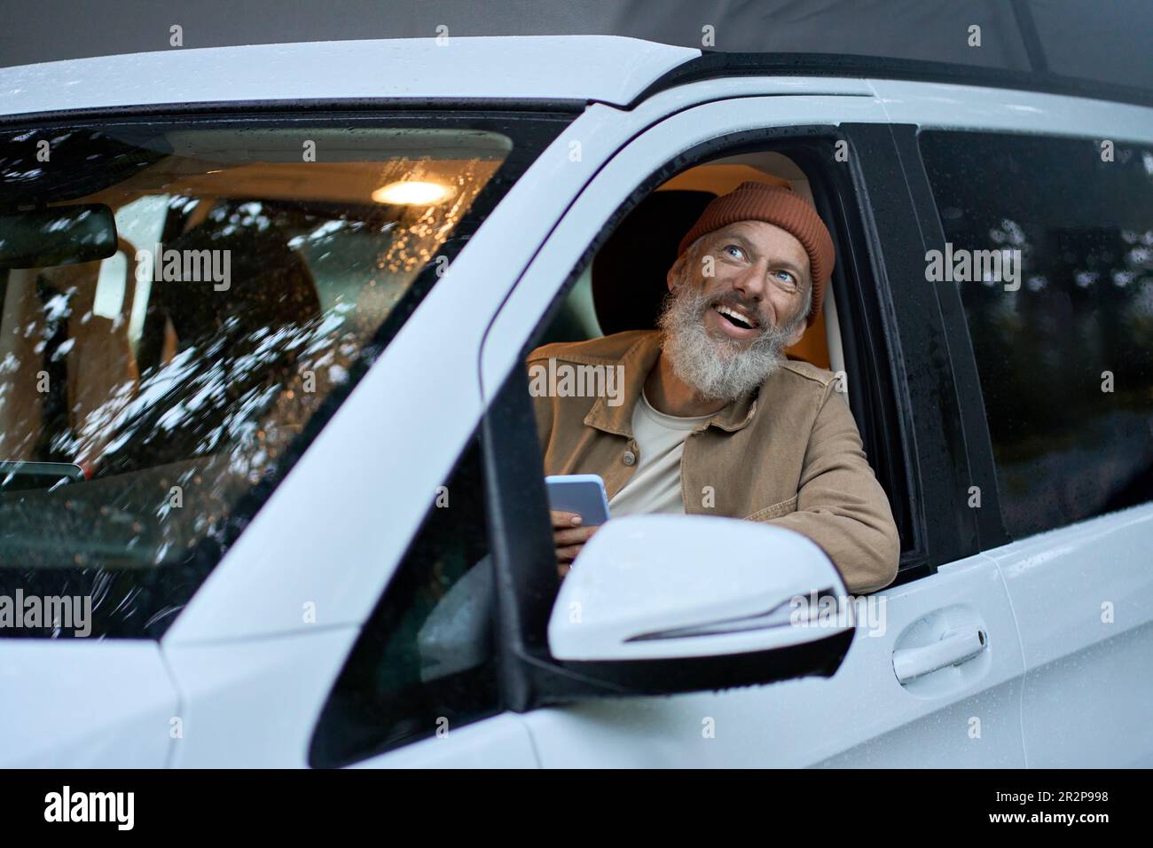 Excited happy older man driving rv camper van looking outside enjoying ...