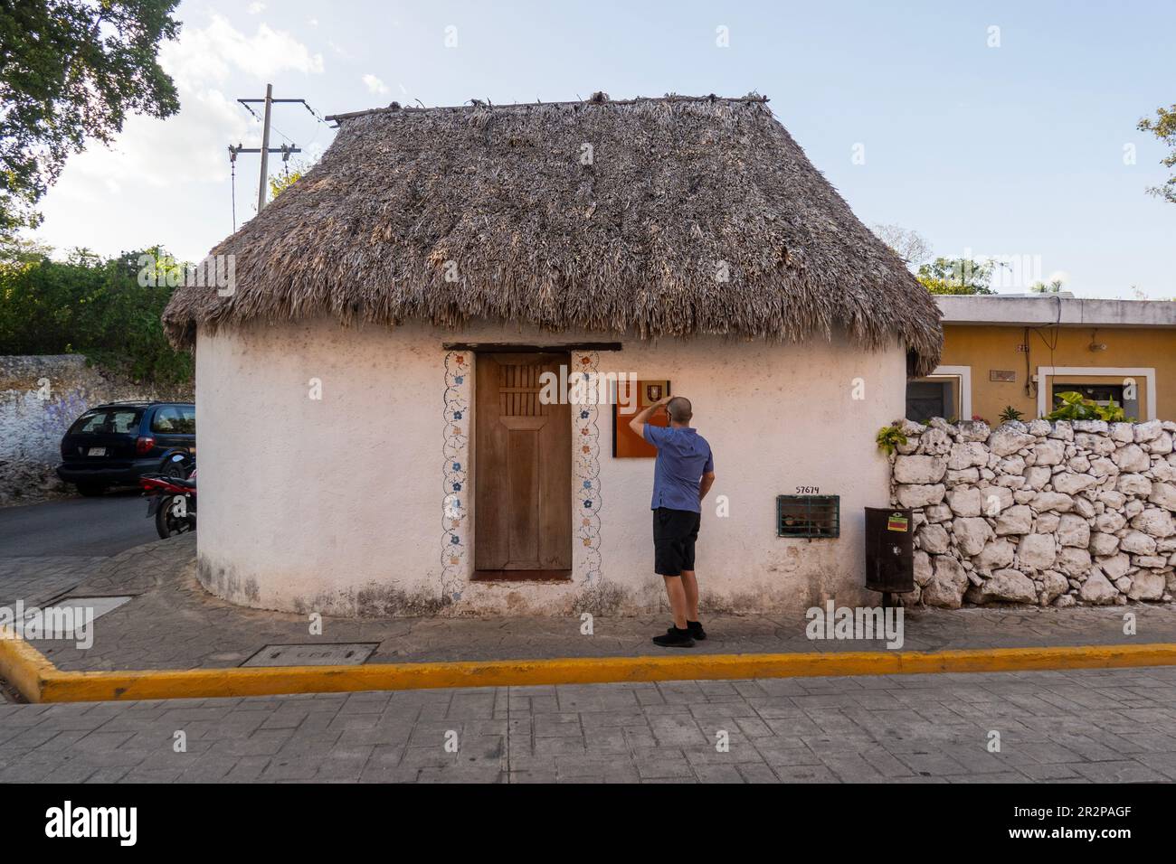 front of a small preserved and restored Mayan house made from materials ...