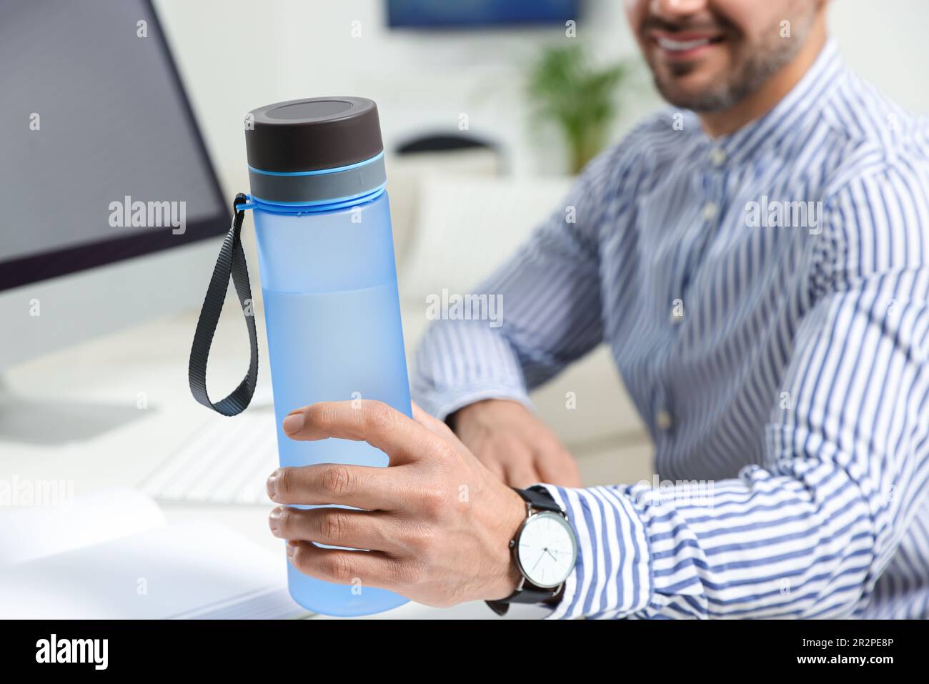 Man taking transparent plastic bottle of water while working on ...