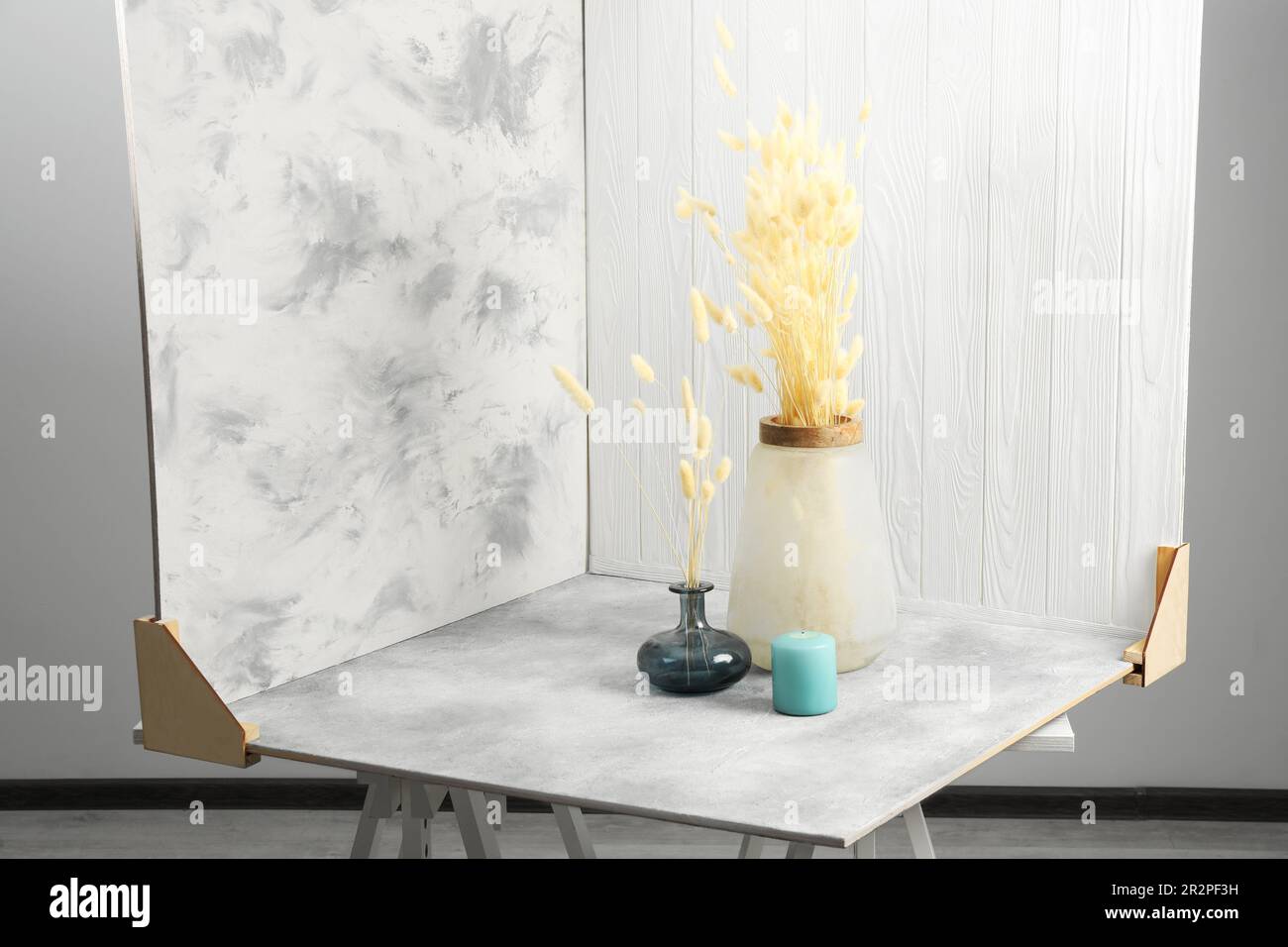 Vases with beautiful dry flowers, candle and double-sided backdrops on ...