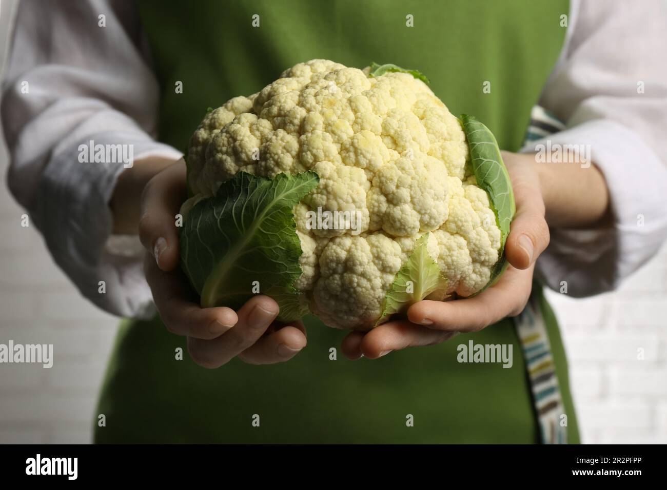 Woman holding fresh cauliflower against brick wall, closeup Stock Photo ...
